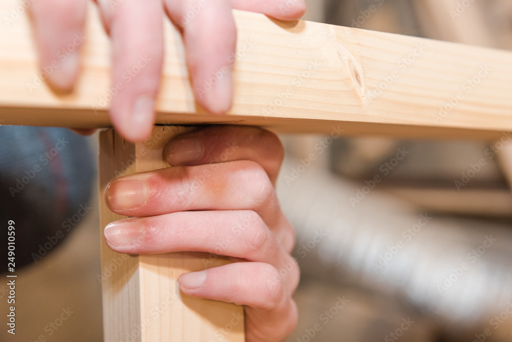 A man is screwing a screw into a wooden table. Carpentry workshop. Work ...