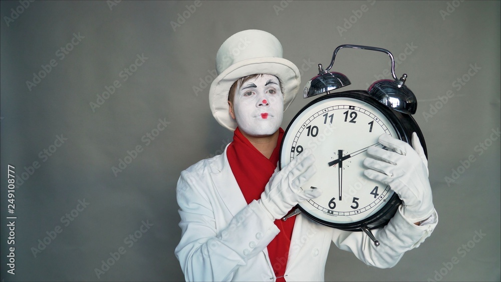 Mime in a suit and hat is holding a big clock. Man in a suit with a ...