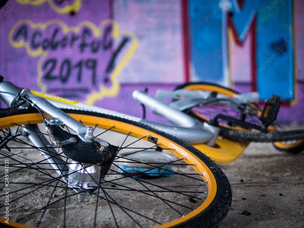 Old yellow scrap bicycles under concrete stairs with violet graffiti ...