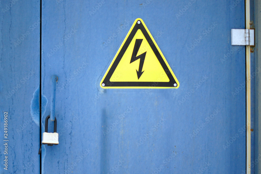Locked electric old metal door with attention sign on the blue wall of ...