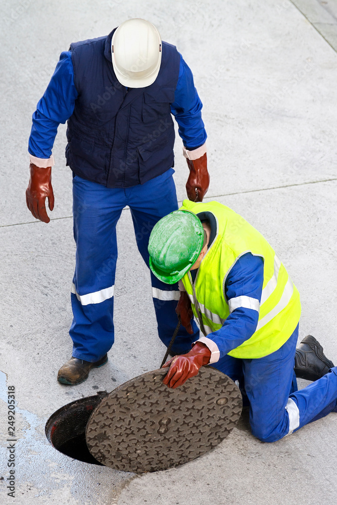 sewerage utility workers moves the manhole cover to cleaning the sewer ...