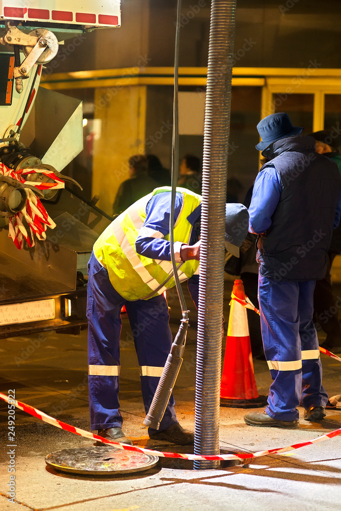 sewerage utility workers moves the manhole cover to cleaning the sewer ...