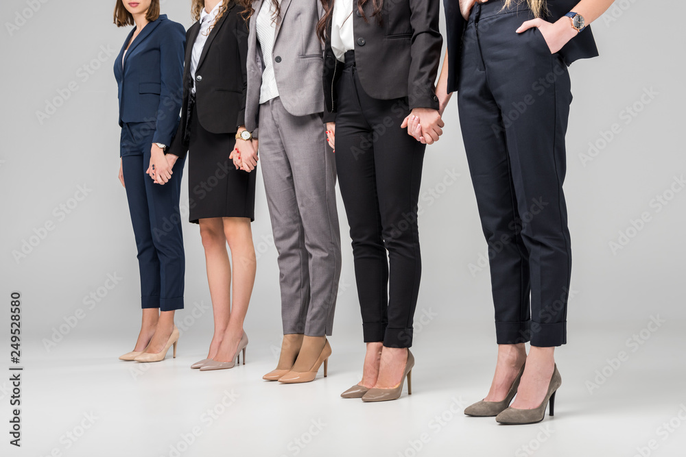 cropped view of women holding hands and standing in hight heel shoes on ...