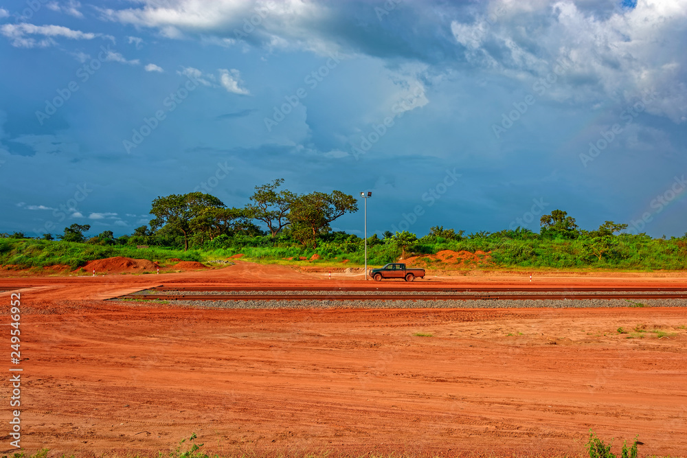 Crossroad of red soils Guinea countryside road and railroad of bauxite ...