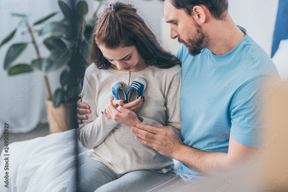 Foto de selective focus of sad husband hugging grieving wife with baby ...