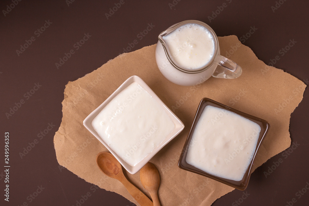 Homemade yogurt in ceramic square bowls, a jug brim full of yogurt ...