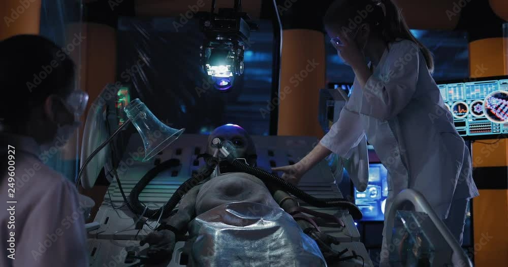 Scientists are examining an alien. Humanoid lying in the laboratory ...