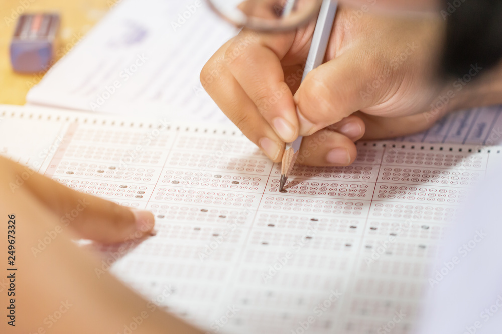 Student taking exams, writing examination on paper answer sheet optical ...