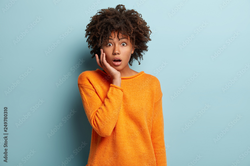 Indoor shot of stupefied frightened woman with dark skin, crisp hair ...
