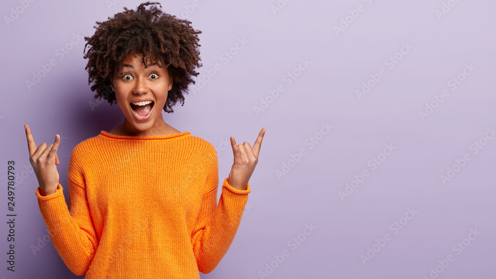Horizontal shot of attractive black woman shows rock n roll sign with ...