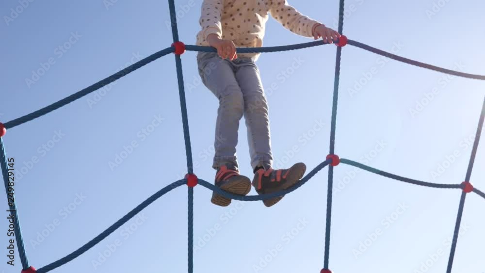 Rope web climbing and crawling little child girl on outdoors playground ...