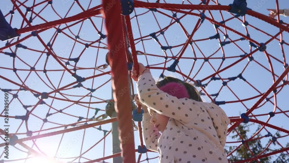 Rope web climbing and crawling little child girl on outdoors playground ...