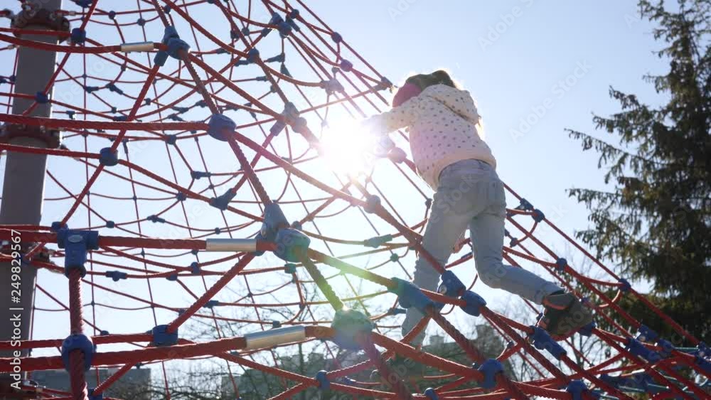 Rope web climbing and crawling little child girl on outdoors playground ...