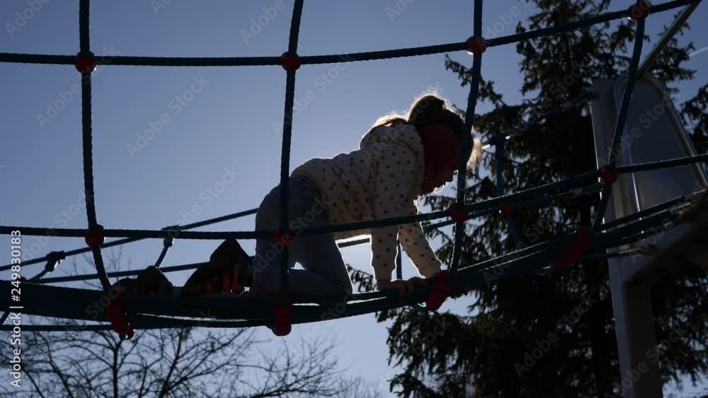 Rope web climbing child girl silhouette in counter light of sun on ...
