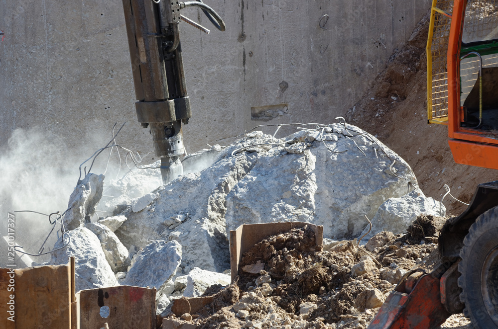 Excavator mounted concrete breaker at work with visible cracks and ...