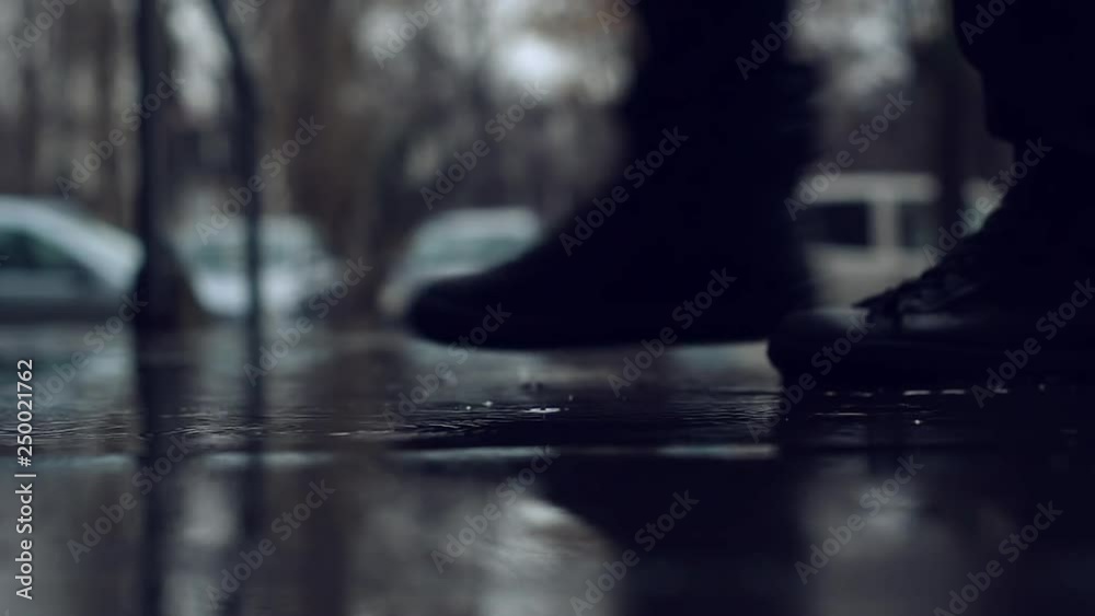 Male feet in boots stepping into rain puddle in the night, man walking ...