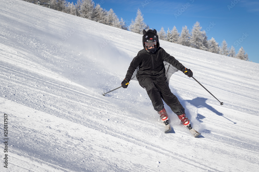 Teenage girl dressed in a bat costume enjoying downhill skiing on a ...