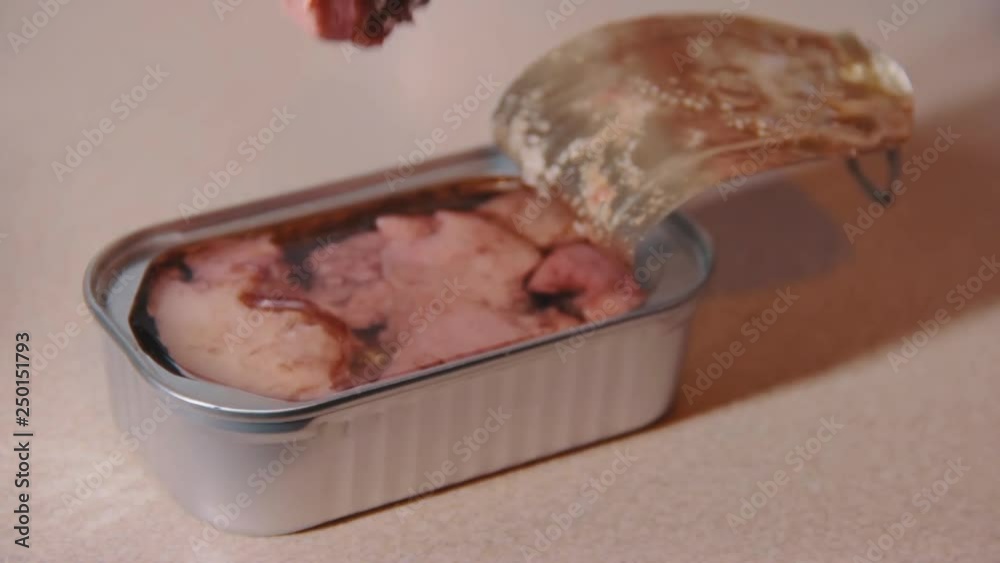 Open can with cod liver oil. From above the fork falls and punctures a ...