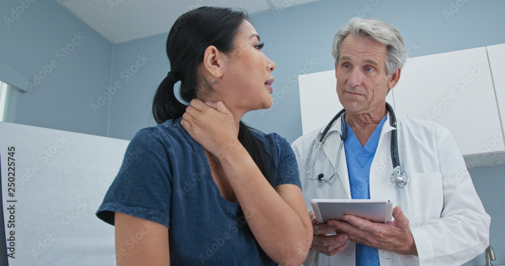 Low angle side view of Asian woman explaining neck pain to doctor in ...