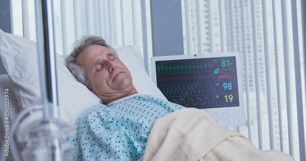 Senior Caucasian male patient lying in hospital bed sleeping with vital ...