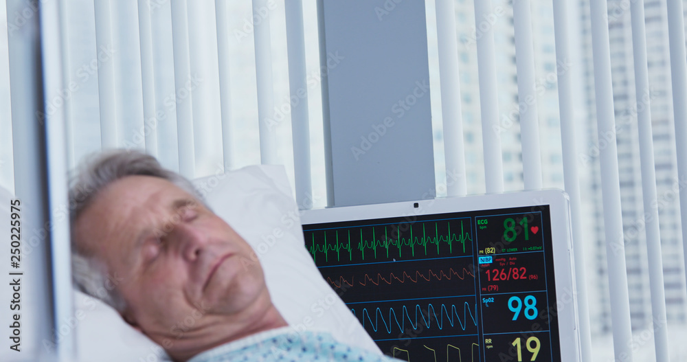 Vital signs monitor with close up of senior Caucasian male patient ...