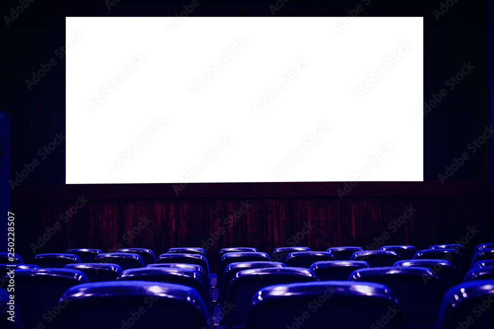Empty cinema auditorium with empty white screen. Empty rows of theater or movie seats. Blue ...