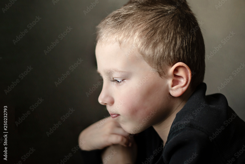 Sad young pre-school boy looking down and thinking. Unhappy child with ...