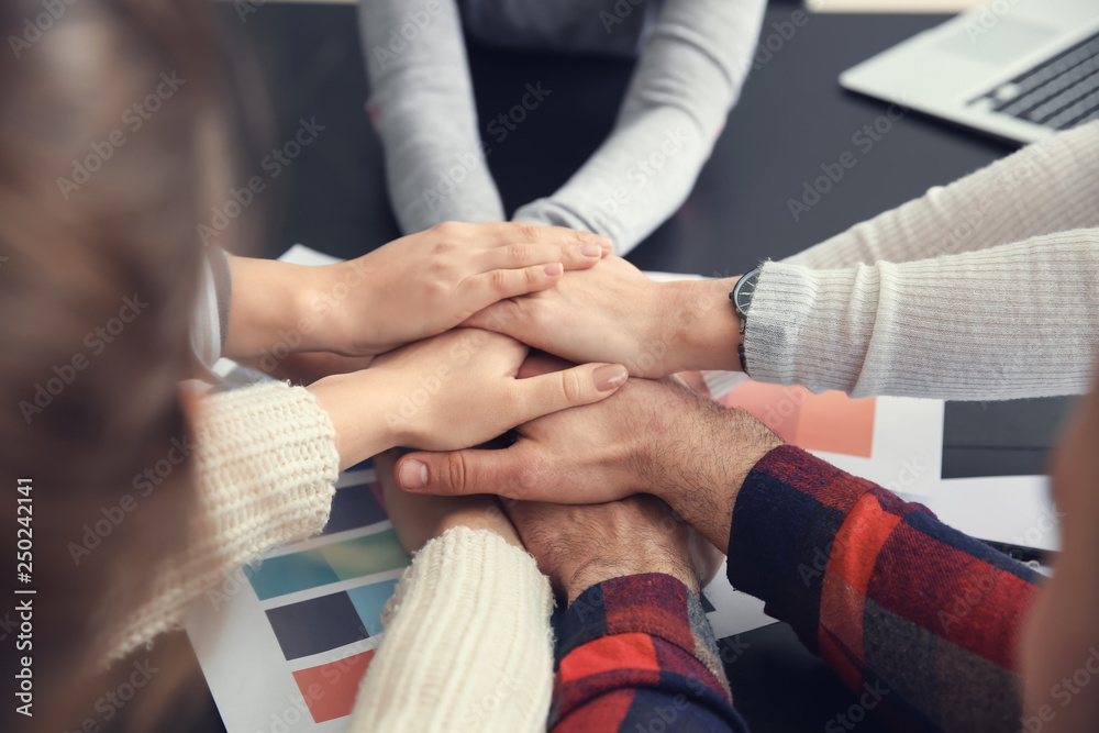Group of people putting hands together as symbol of unity in office ...
