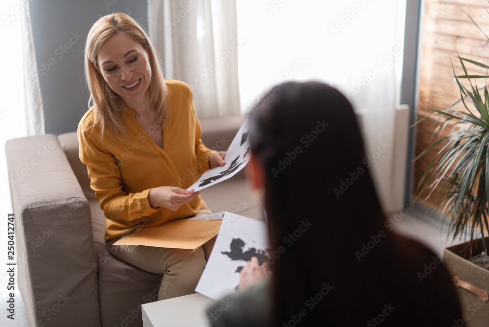 Smiling psychologist holding Ink blot test during seance with patient ...