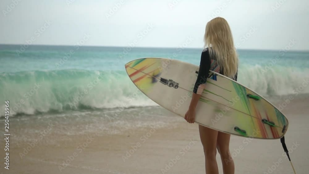 Vídeo do Stock: side view of blonde female surfer facing the blue ocean ...