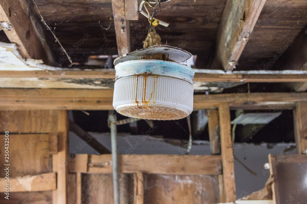 Lighting fixture hanging from support beam in abandoned house formally ...