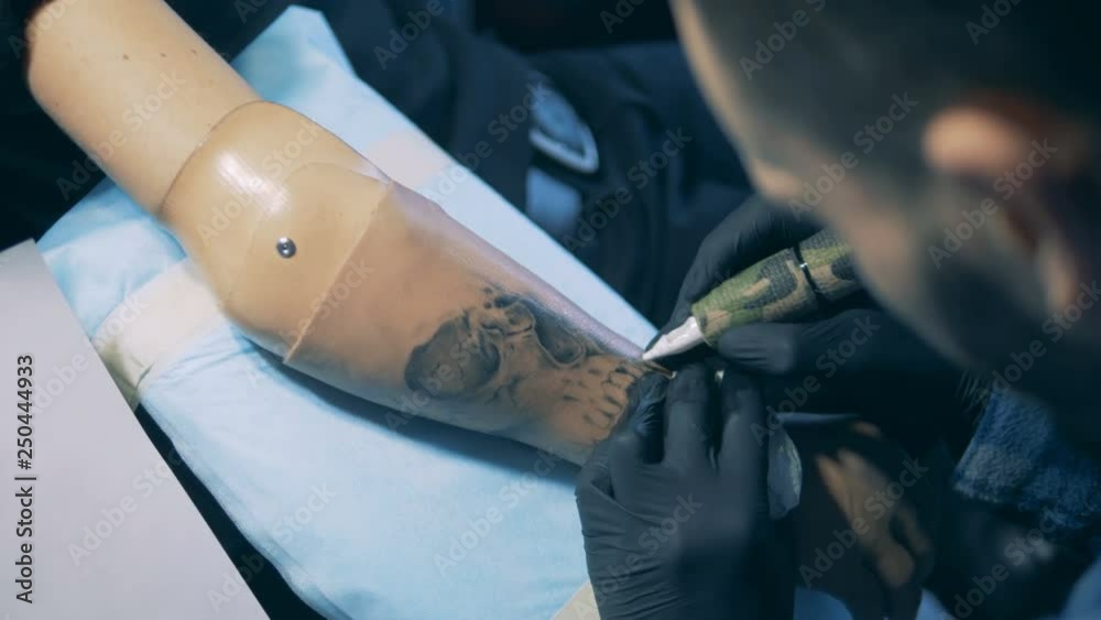 Black-ink tattoo is being made on a male prosthetic arm Stock Video ...