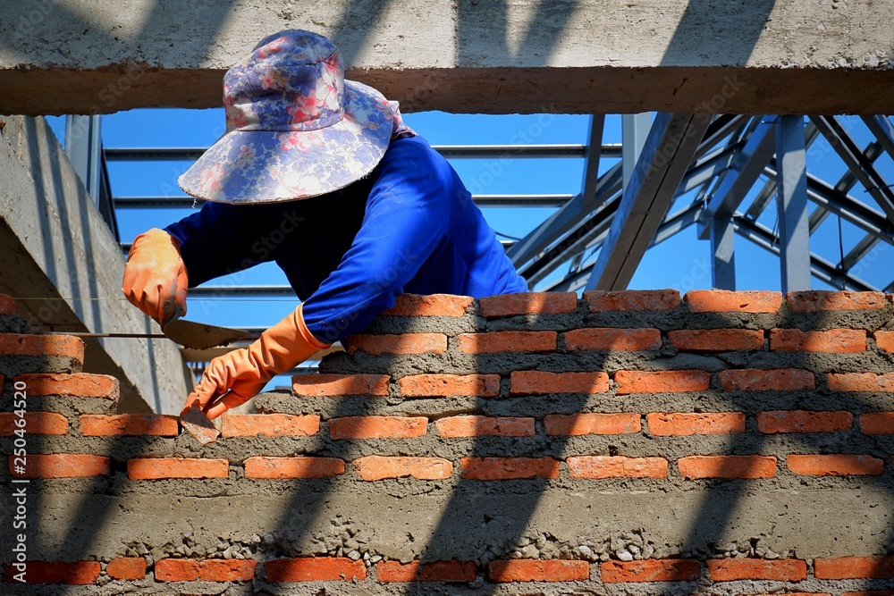 Sunlight and shadow on surface of female bricklayer in blue long sleeve ...