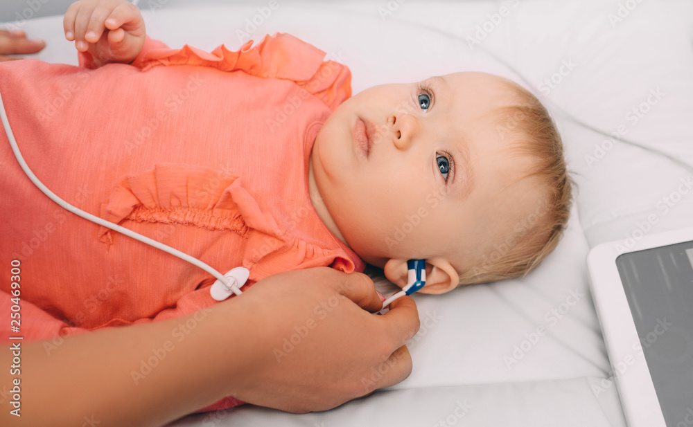 doctor check a baby girl's ears. Little baby having hearing test ...