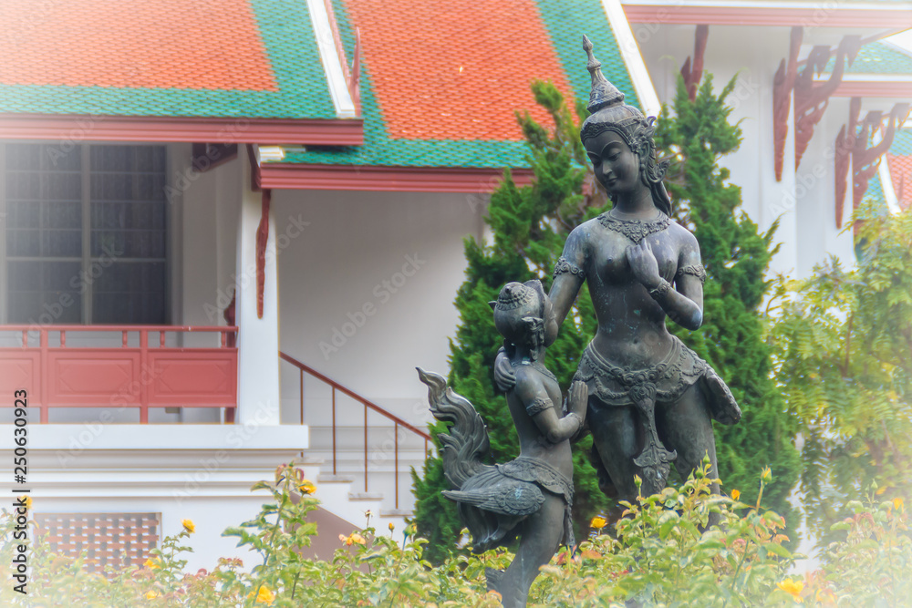 Cute bronze mother and son kinnaree sculptures in the green garden at ...