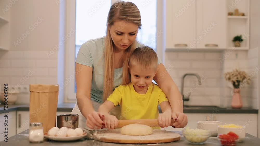 The little beautifull blond boy helps mother to cook. Mom and son in ...