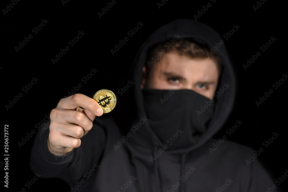 Closeup hacker with blurred face hold bitcoin in hand initiating cyber ...