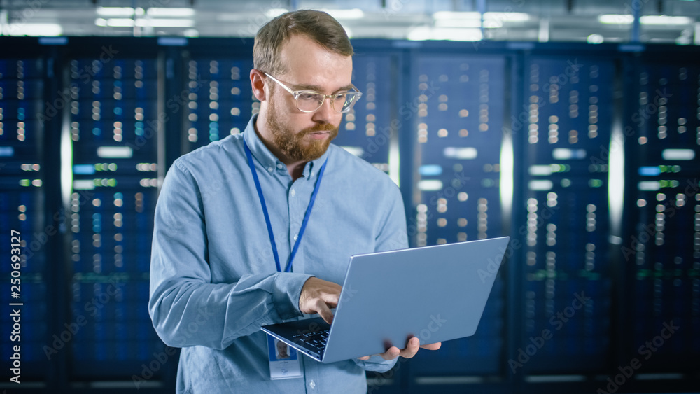 Bearded IT Specialist in Glasses is Working on Laptop in Data Center ...