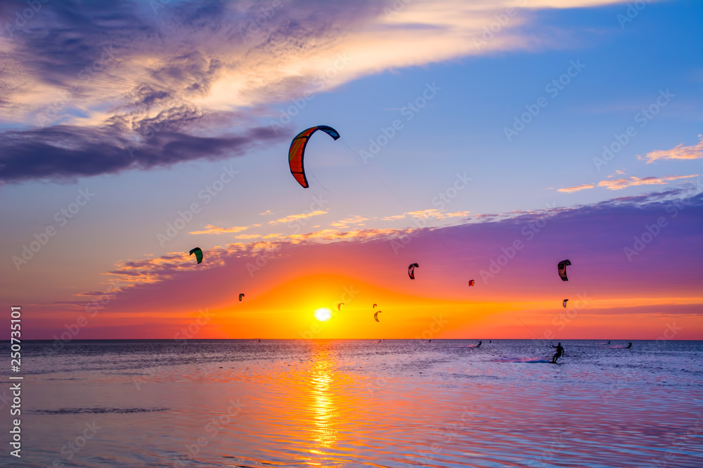 Kite-surfing against a beautiful sunset. Many silhouettes of kites in ...