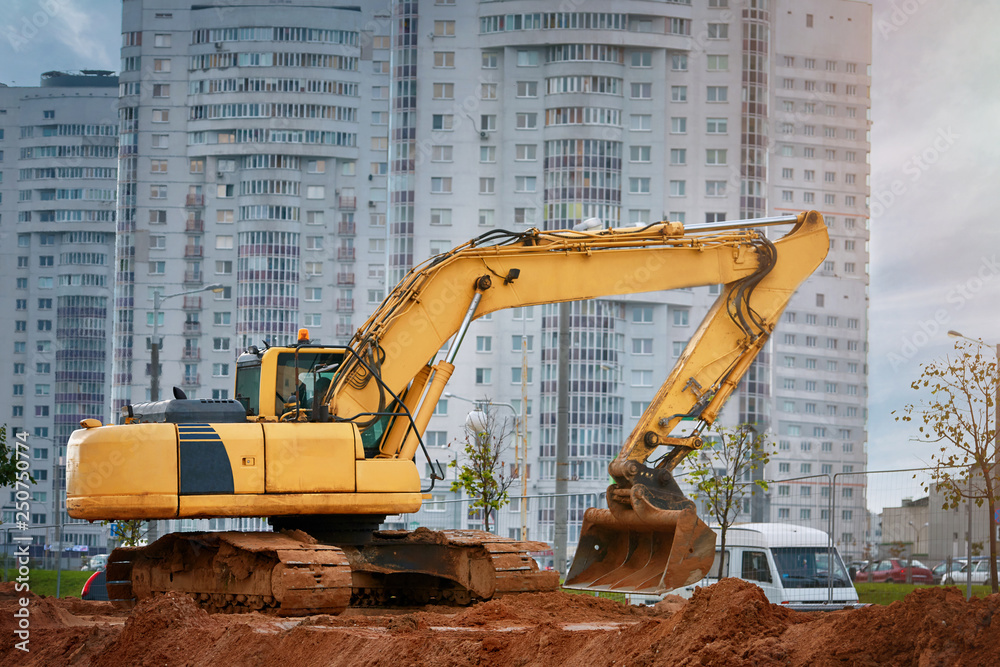 Yellow heavy duty digger on background of residential complex. Large ...