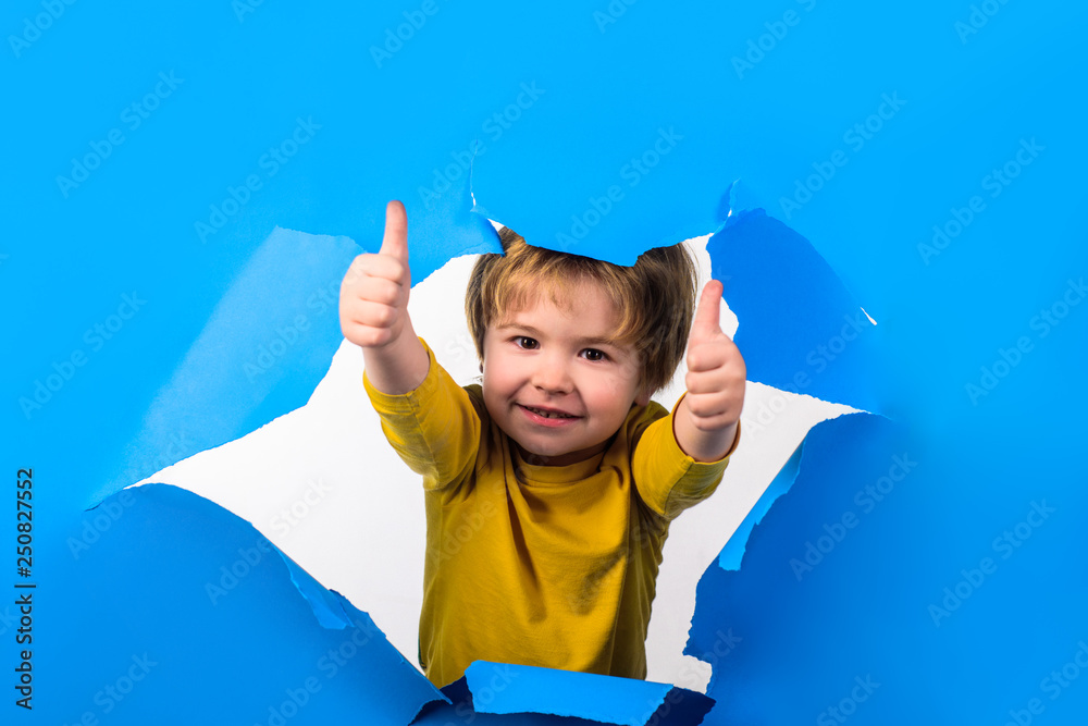Happy childhood. Boy breaking through paper showing thumbs up. Happy ...