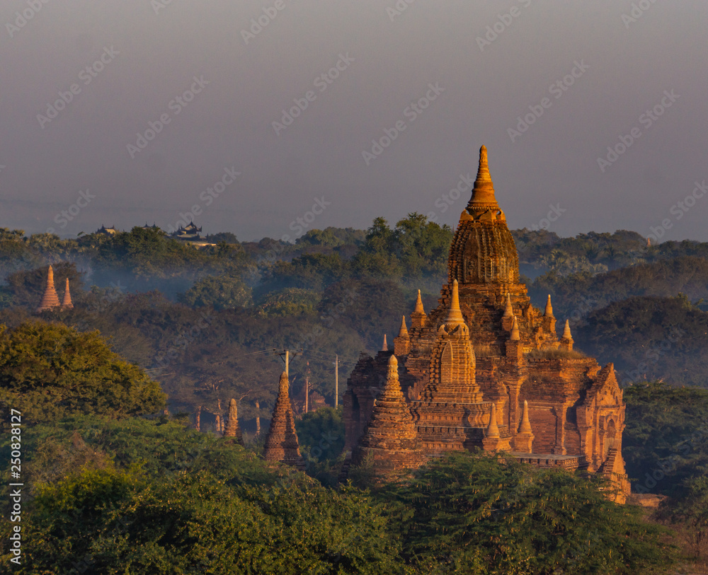 rising sun lighting up ancient historic Pagodas in old Bagan at dawn ...