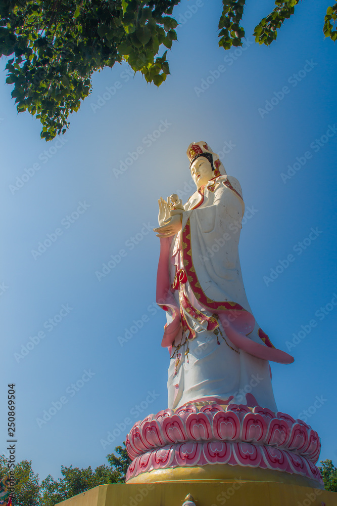 Giant white Guanyin statue with blue sky background. Guanyin or Guan ...