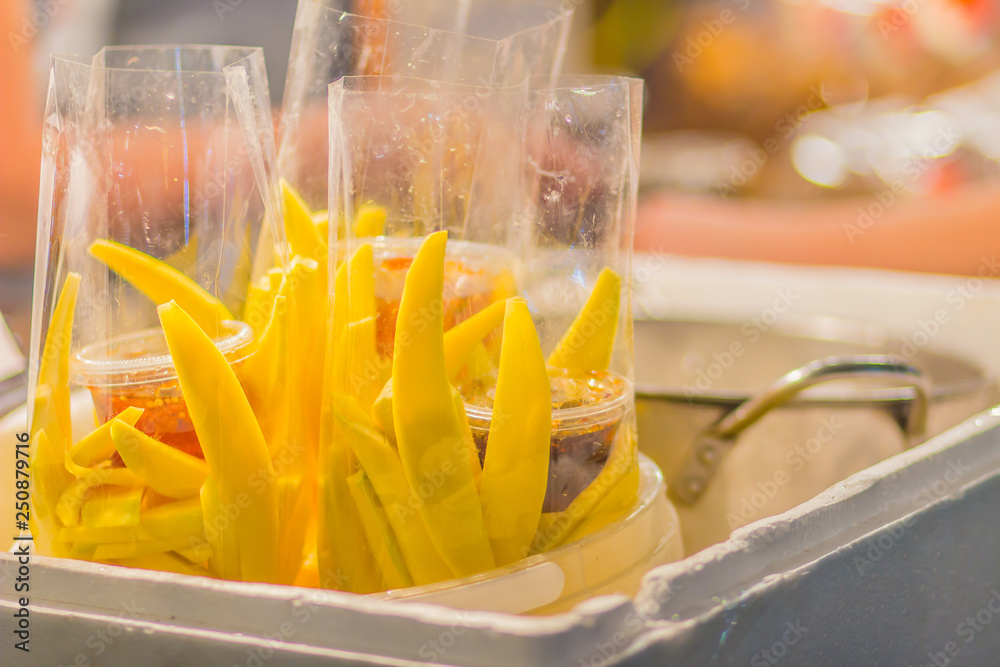 Yellow sliced mango in plastic bag with sweet sauce for sale at the ...