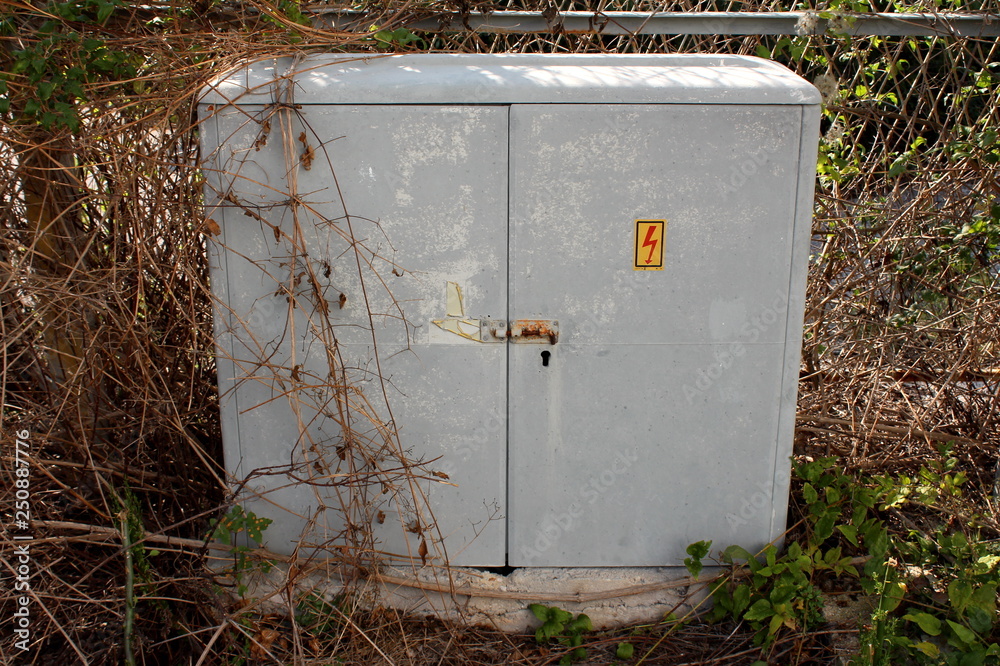 Grey electrical high voltage outdoor box closed with rusted latch ...