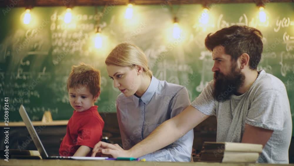 Parents with their son working with laptop sitting in classroom on ...