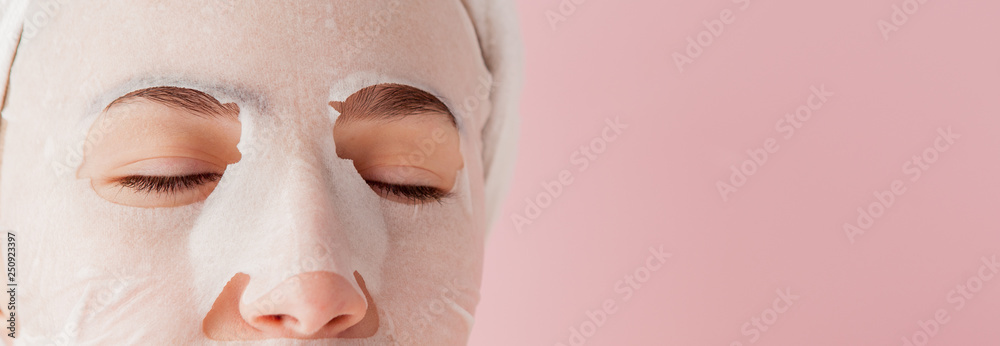 Beautiful young woman is applying a cosmetic tissue mask on a face on a ...