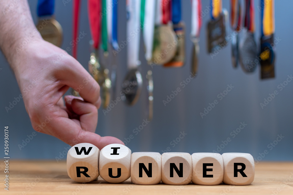 Hand turns a dice and changes the word "RUNNER" to "WINNER" in front of ...