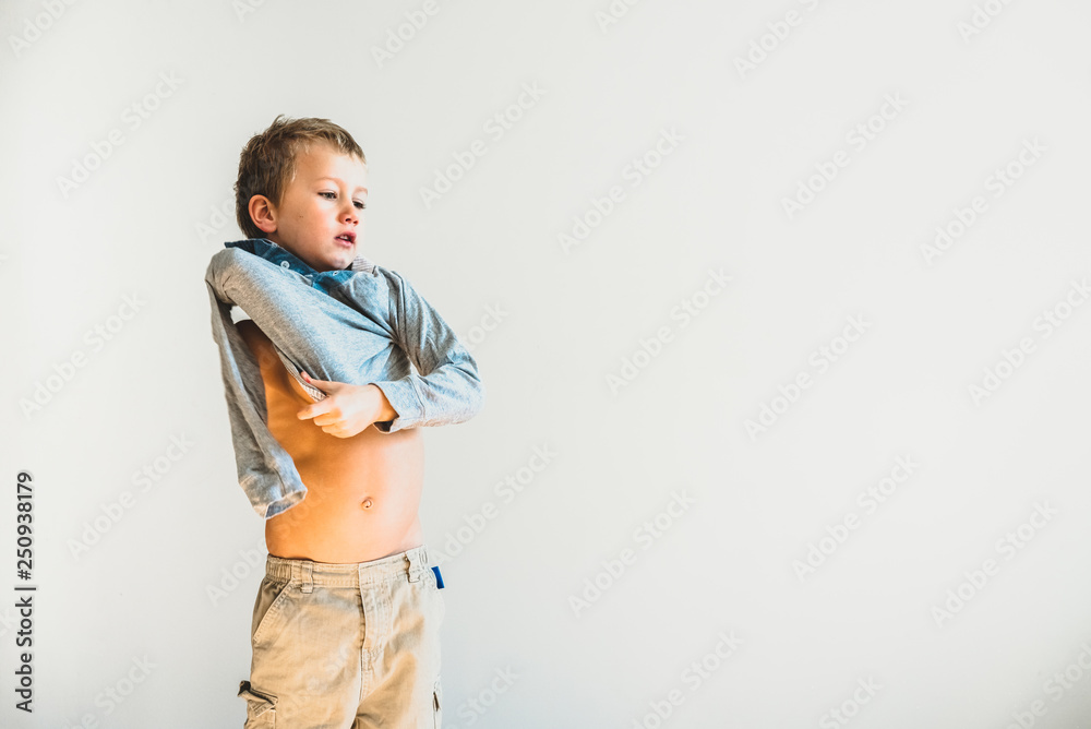 Child trying to take off his shirt and undress on his own. Stock Photo ...