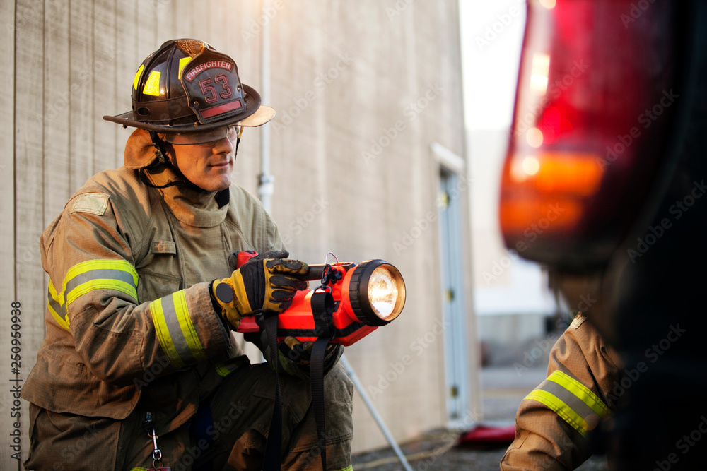 Firefighter using flashlight on car crash site Stock Photo | Adobe Stock